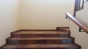 Escada com degraus de madeira e azulejos decorativos na base.