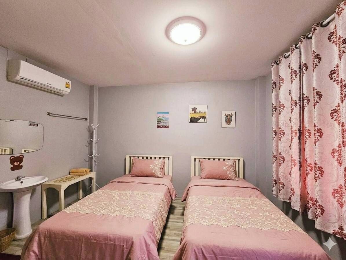 Quarto com duas camas, uma mesinha de cabeceira, um espelho, uma pia e ar-condicionado fixado na parede.