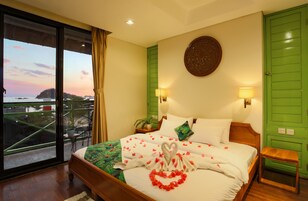 Quarto de hotel com uma cama, um guarda-roupa verde, uma porta verde e vista para o mar.