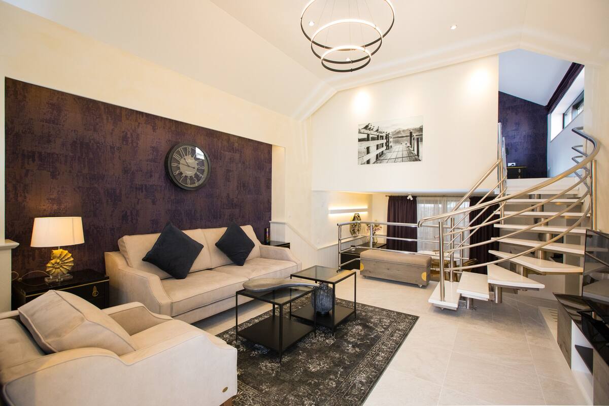Uma sala de estar moderna com um sofá, mesa de centro e escada.