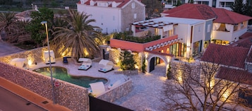 Uma área de piscina externa luxuosa com espreguiçadeiras e um muro de pedra.