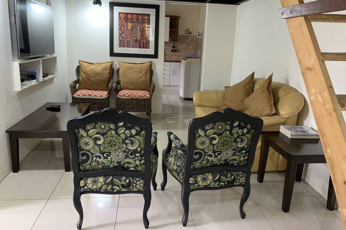 Uma sala de estar com um sofá, duas poltronas, uma mesa de centro, uma televisão e um quadro na parede.