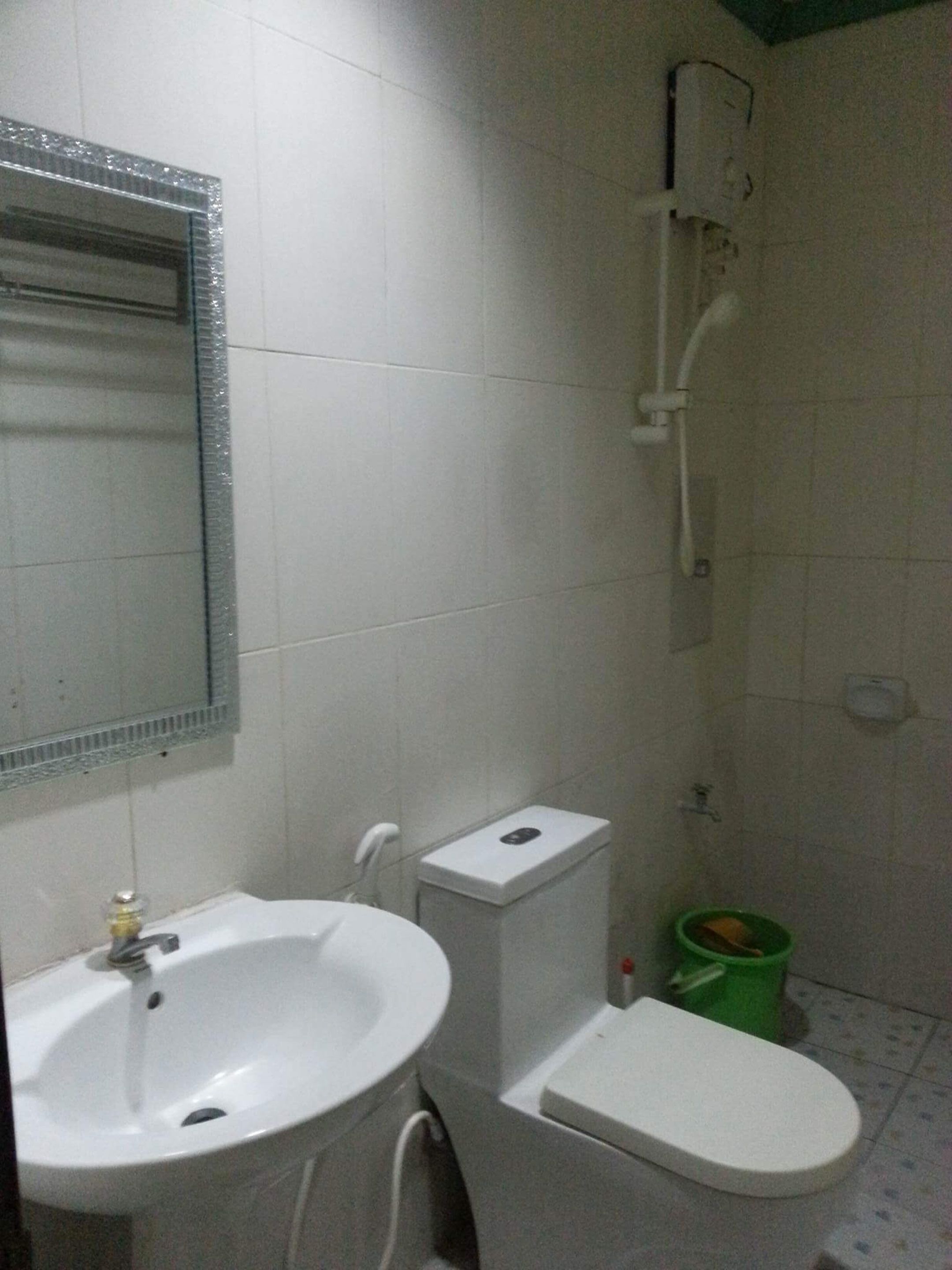 Um banheiro pequeno com pia, vaso sanitário e chuveiro brancos.