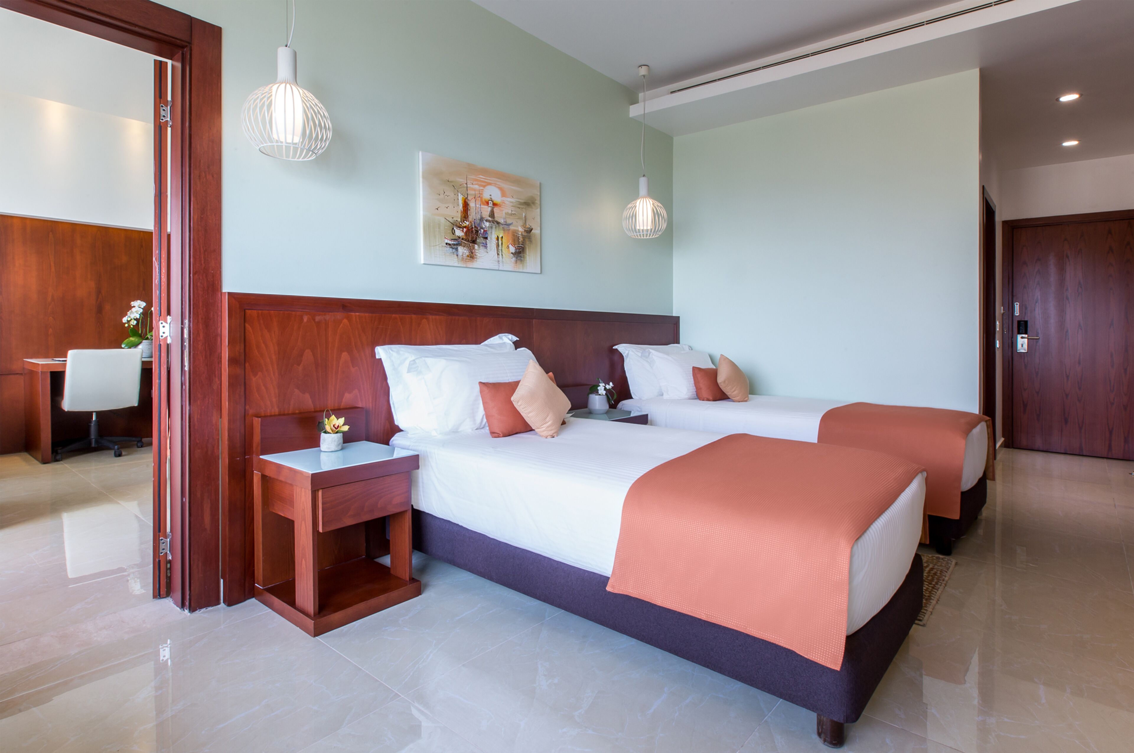 Quarto de hotel com uma cama grande, mesas de cabeceira, uma escrivaninha e uma cadeira.