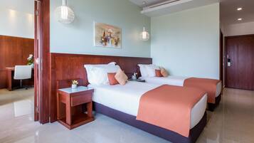 Quarto de hotel com uma cama grande, mesas de cabeceira, uma escrivaninha e uma cadeira.