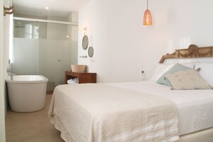 Quarto com cama, cabeceira de madeira, mesa de cabeceira e espelho fixado na parede.
