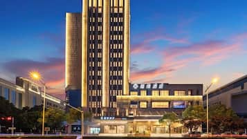 Um hotel moderno com uma estrutura vertical imponente e um edifício horizontal com sinalização.