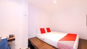 Quarto de hotel com uma cama, uma escrivaninha e uma cadeira.
