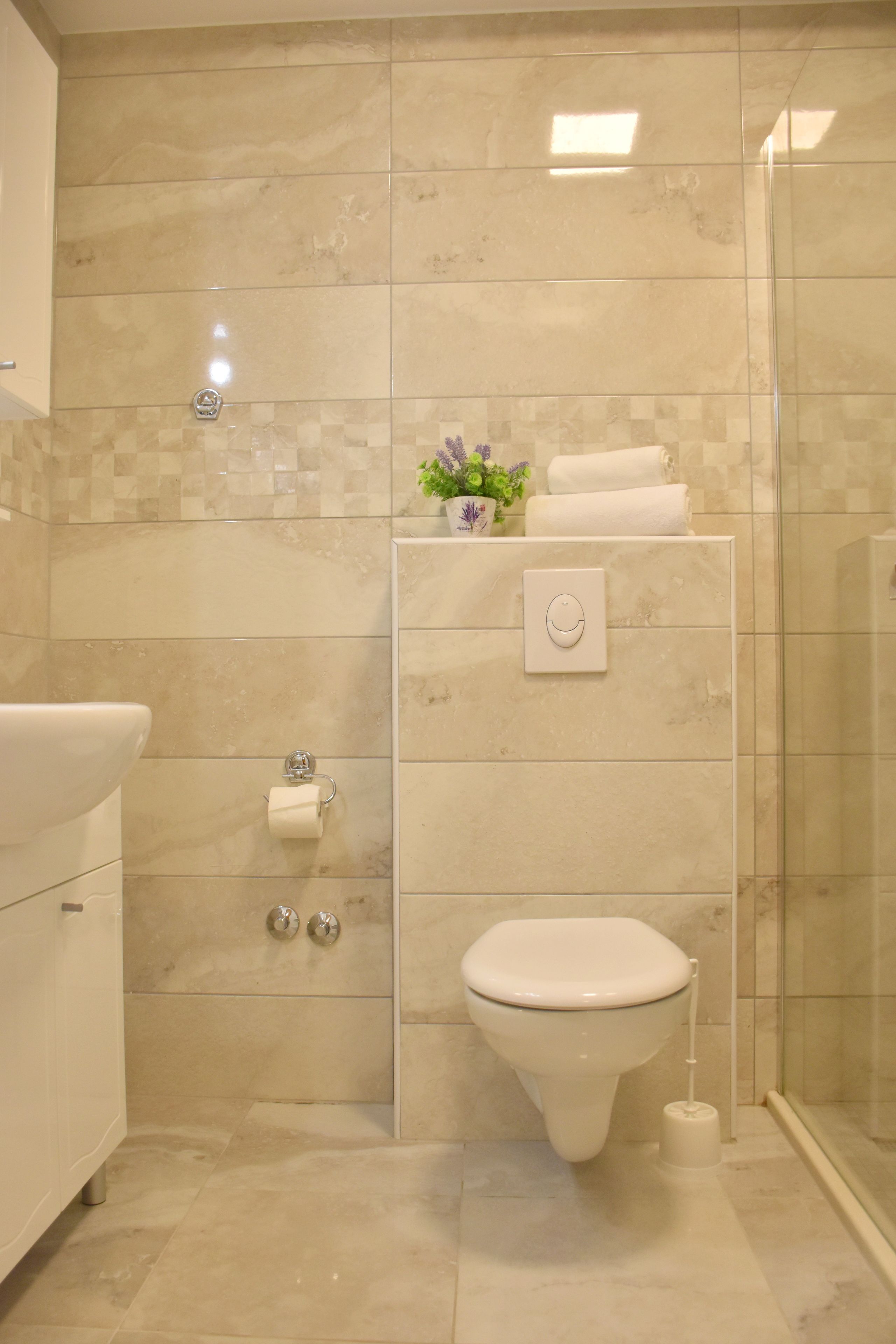 Casa de banho moderna com sanita, bidé e cabine de duche em vidro.