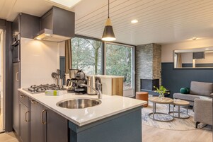 Cozinha moderna com uma ilha grande, eletrodomésticos de aço inoxidável e vista para o exterior.