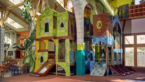 Uma área de recreação com estruturas para escalar, escorregadores e uma parede de escalada em árvore.