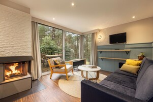 Uma sala de estar moderna com lareira, sofá, mesa de centro e televisão fixada na parede.