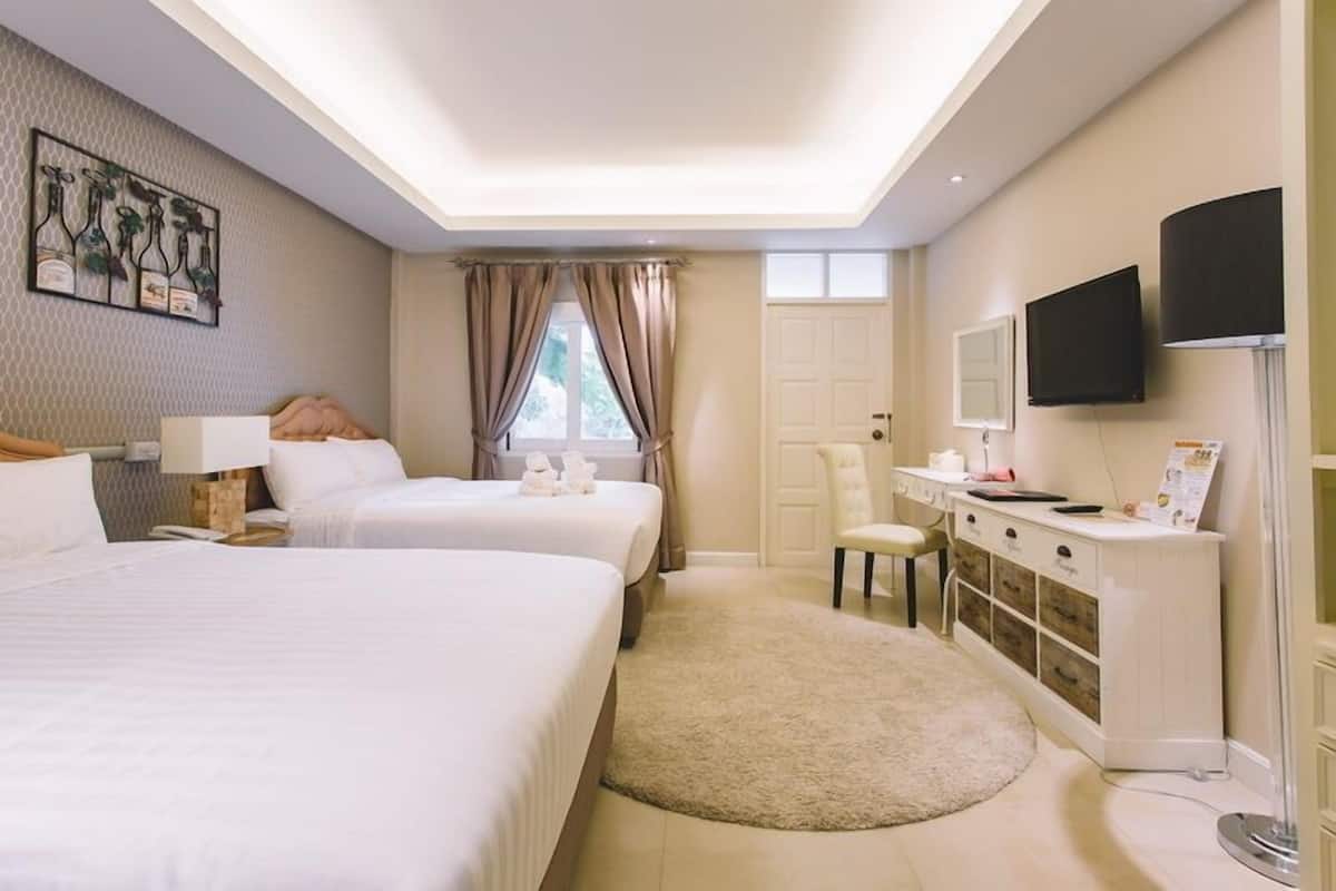 Quarto de hotel com duas camas, uma escrivaninha, uma cadeira, uma televisão e uma janela com cortinas.