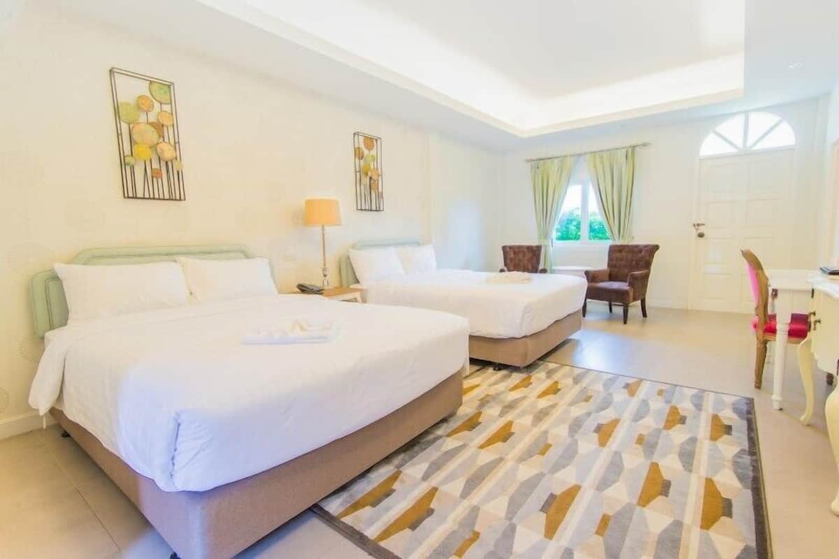 Quarto de hotel com duas camas, um tapete estampado, uma escrivaninha e uma cadeira.