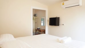 Quarto de hotel com uma cama grande, uma televisão de tela plana na parede e um aparelho de ar condicionado acima.