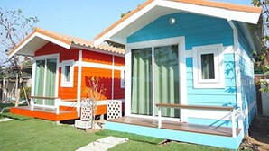 Uma casa de dois andares com fachada vermelha e azul, janelas amplas e varanda.