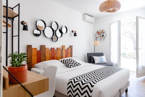 Quarto moderno com cama, mesa de cabeceira, planta em vaso, espelhos fixados na parede e vista para o exterior.