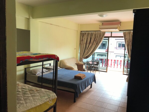 Quarto em dormitório com beliches, uma mesa pequena, cadeiras e uma varanda com vista.