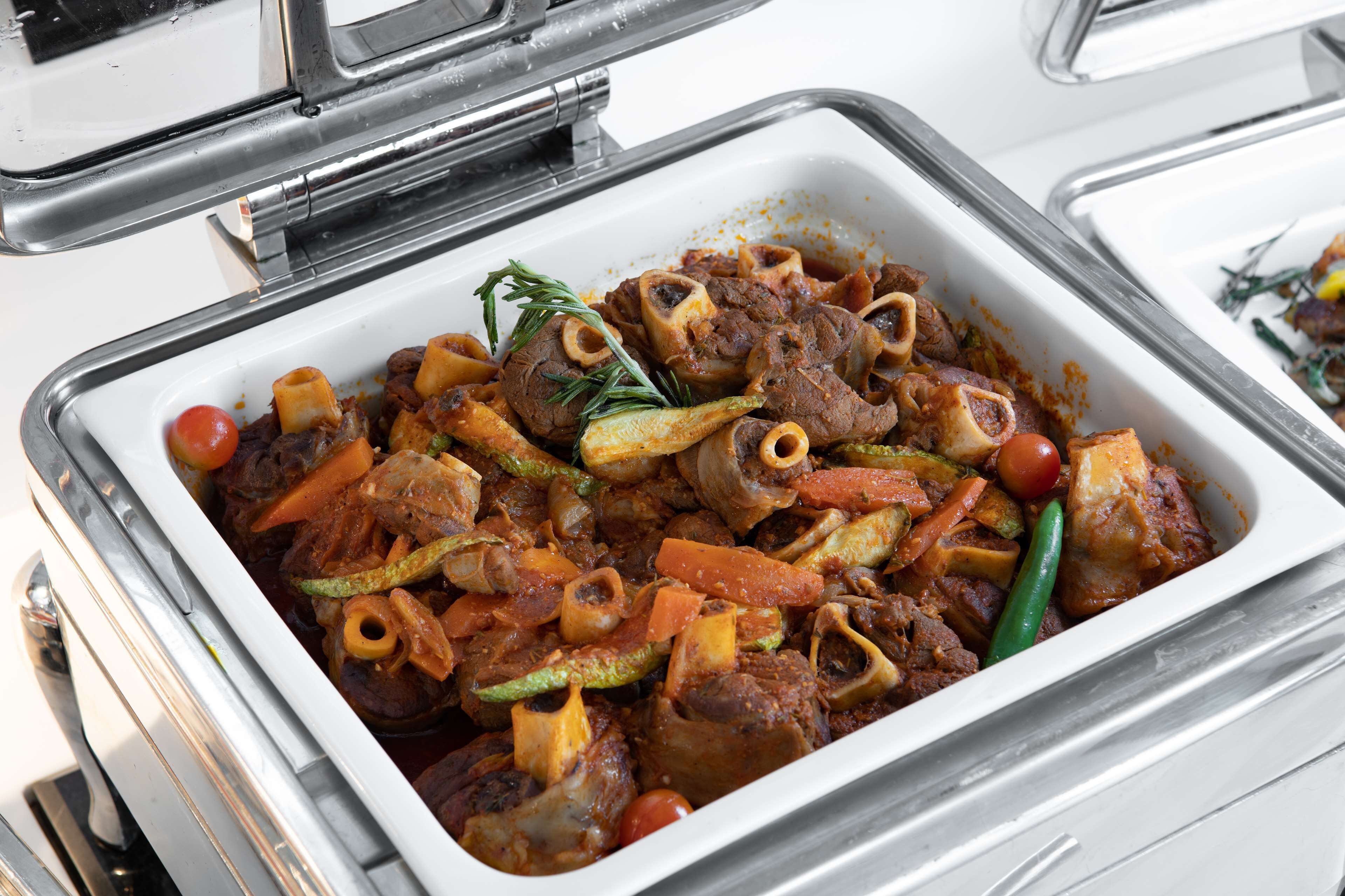 Buffet com variedade de pratos, incluindo carne e legumes.