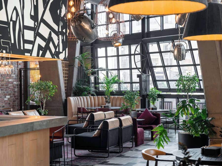 Um interior moderno com área de bar, assentos e grandes janelas.
