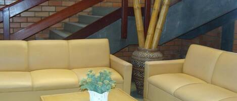 Sala de estar com sofá bege, uma mesinha de centro e um vaso decorativo com raminhos de bambu.