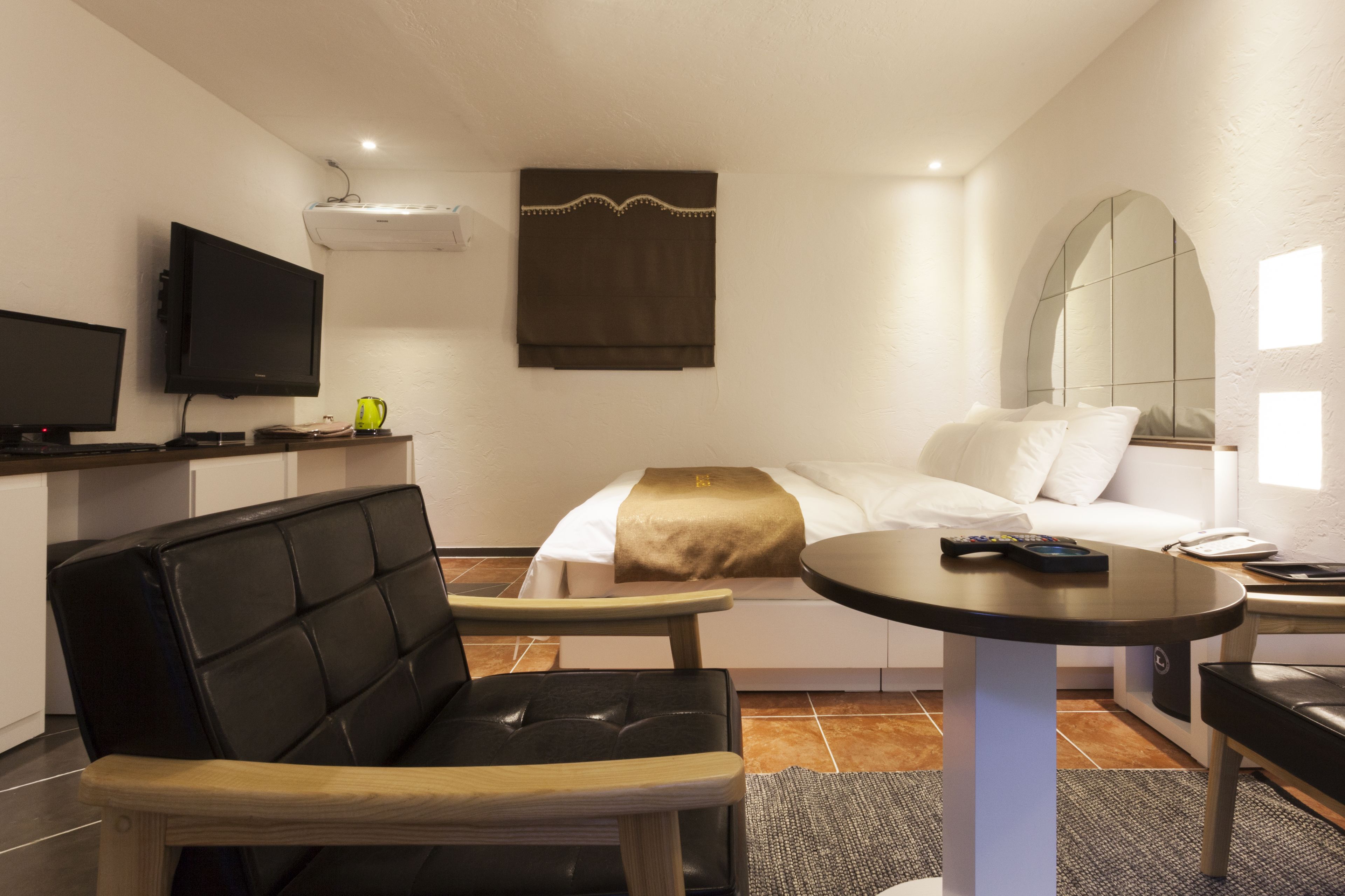 Quarto de hotel com cama, televisão, escrivaninha e cadeira.