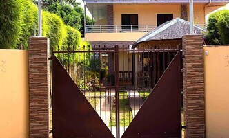 Uma entrada murada para uma propriedade residencial, com muro de tijolos, portão de metal e uma pequena cobertura sobre o portão.