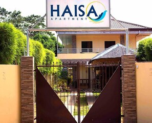 Uma entrada com portão para um prédio residencial, com uma placa indicando "HAISA APARTMENT".