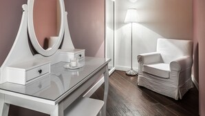 Quarto com toucador, cadeira, luminária e espelho.