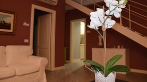 Uma sala de estar com um sofá branco, uma escada e uma orquídea em vaso.