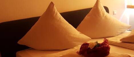 Uma cama com duas almofadas e um tecido vermelho na colcha.