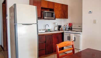 Cozinha compacta com geladeira, micro-ondas, pia, fogão e armários de madeira.