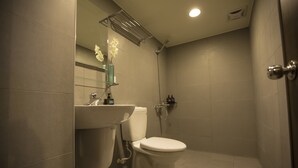 Casa de banho moderna com sanita, lavatório e chuveiro.