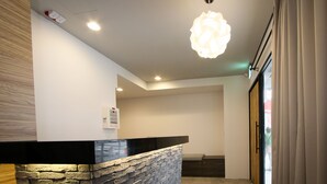 Uma área de recepção com parede de pedra, balcão preto e luminária pendente.