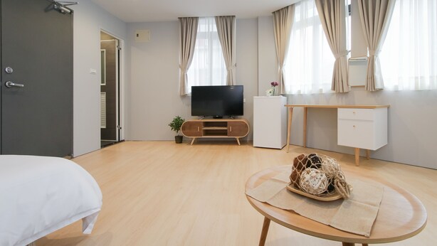 Quarto de hotel moderno com cama, televisão, secretária e mesa de jantar.