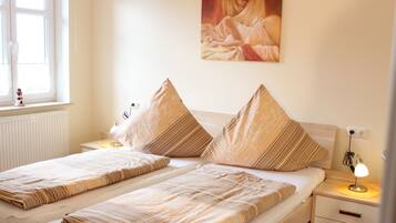 Uma cama de casal com roupa de cama listrada, uma mesa de cabeceira com abajur e um quadro na parede.