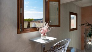 Um interior moderno com uma mesa de vidro, uma cadeira transparente e uma planta decorativa sobre um console branco.