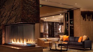 Um lobby moderno com uma lareira grande, assentos confortáveis e vista para a sala de jantar.