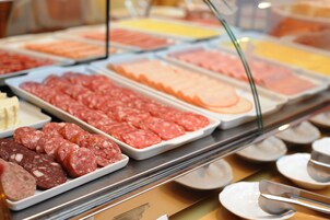 Balcão de charcutaria com diversos tipos de carnes fatiadas expostas em bandejas.