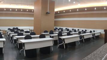 Uma sala de conferências com mesas e cadeiras dispostas em fileiras, um púlpito e um extintor de incêndio.