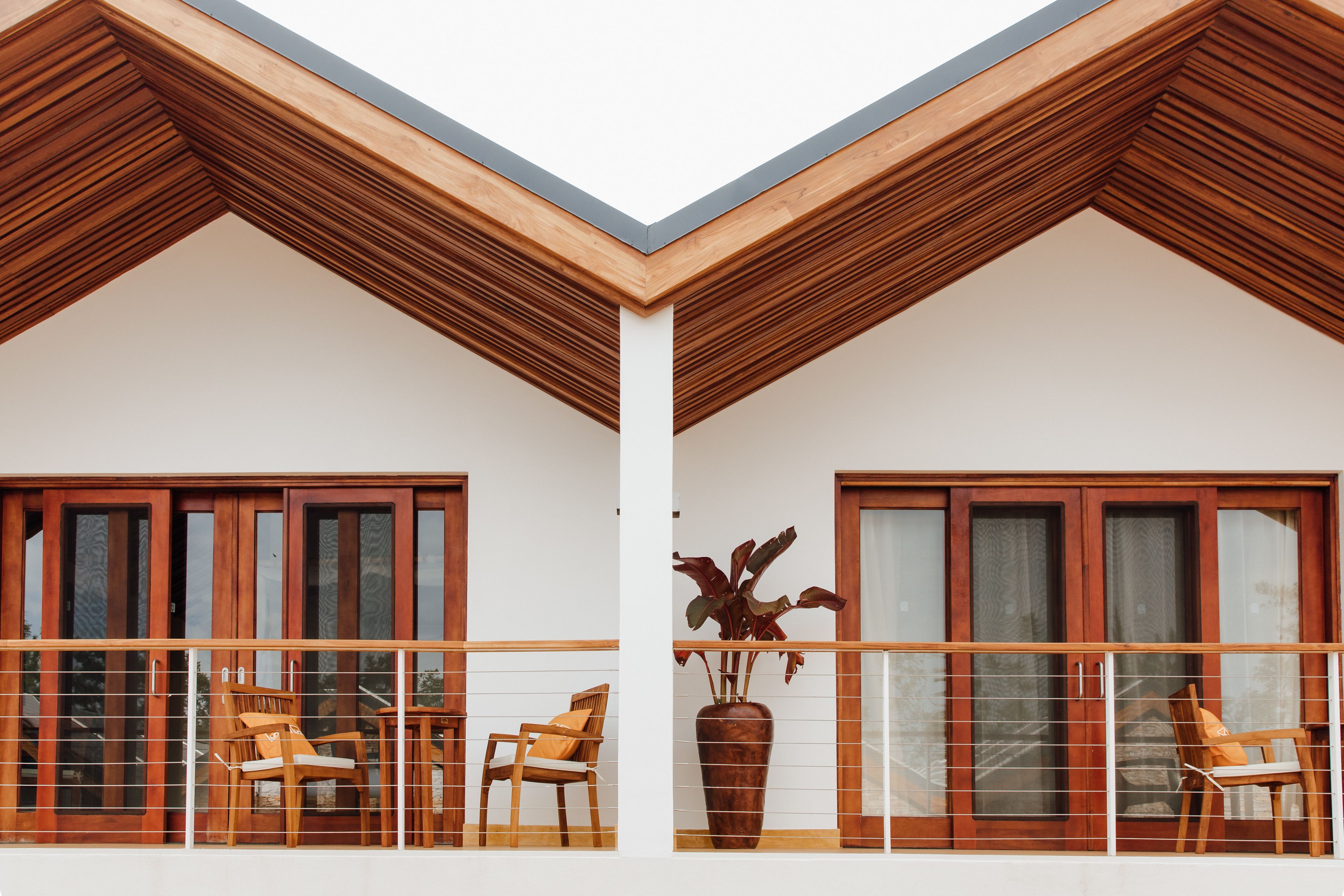 Um edifício moderno com design simétrico, com grandes janelas e uma varanda com móveis de madeira.