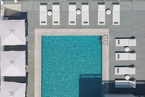 Vista aérea de uma área de piscina no terraço, com vários espreguiçadeiras e uma piscina.