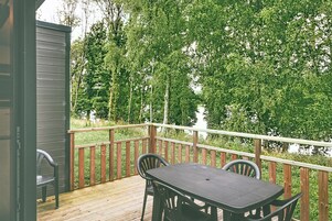 Um deck de madeira com mesa e cadeiras, com vista para uma área arborizada.