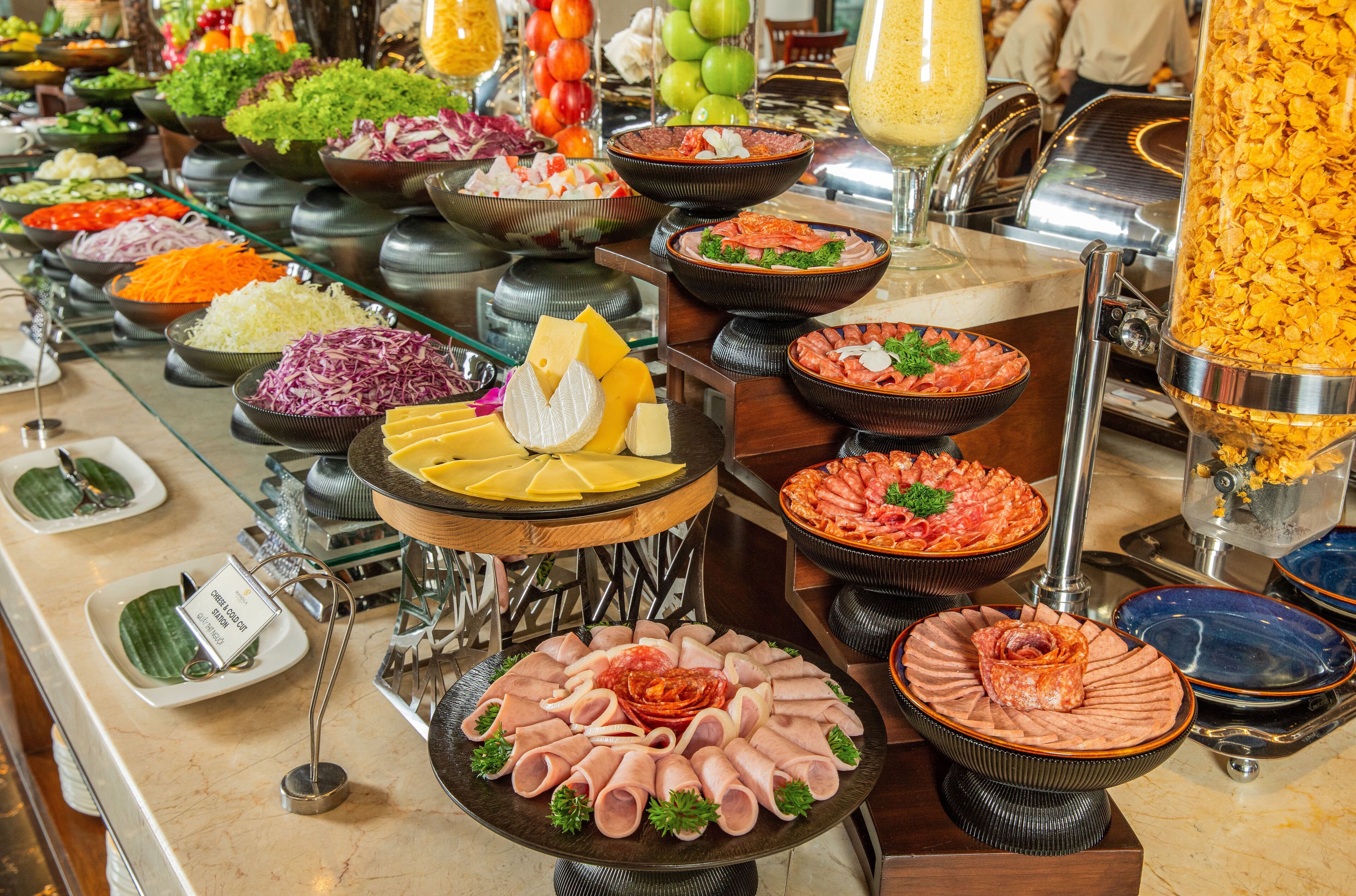 Buffet com diversas opções de comida, incluindo carnes, queijos e vegetais.