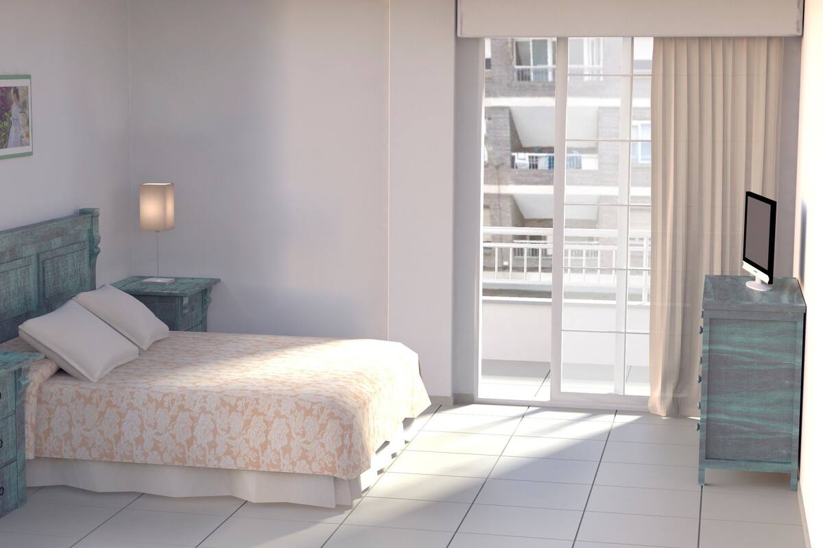 Quarto com cama, mesas de cabeceira, luminária, televisão e varanda com vista para edifícios.