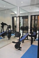 Academia com equipamentos de musculação e bancos para exercícios.