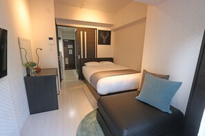 Quarto de hotel moderno com uma cama, um sofá, uma escrivaninha e um espelho.