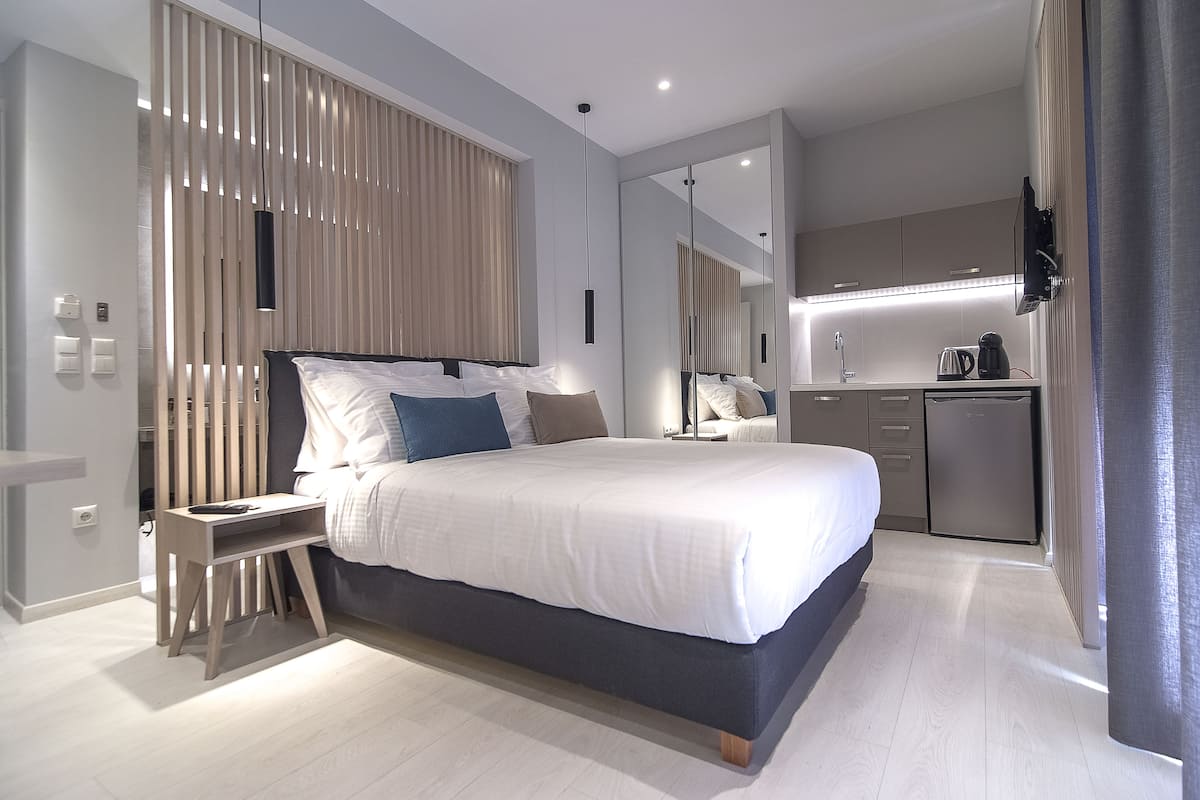 Quarto moderno com cama grande, mesas de cabeceira, guarda-roupa embutido e cozinha compacta.