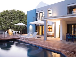 Uma casa moderna com piscina, área de estar externa e um alpendre coberto.