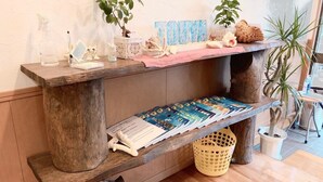 Um console de madeira com revistas, uma pequena planta e objetos decorativos.